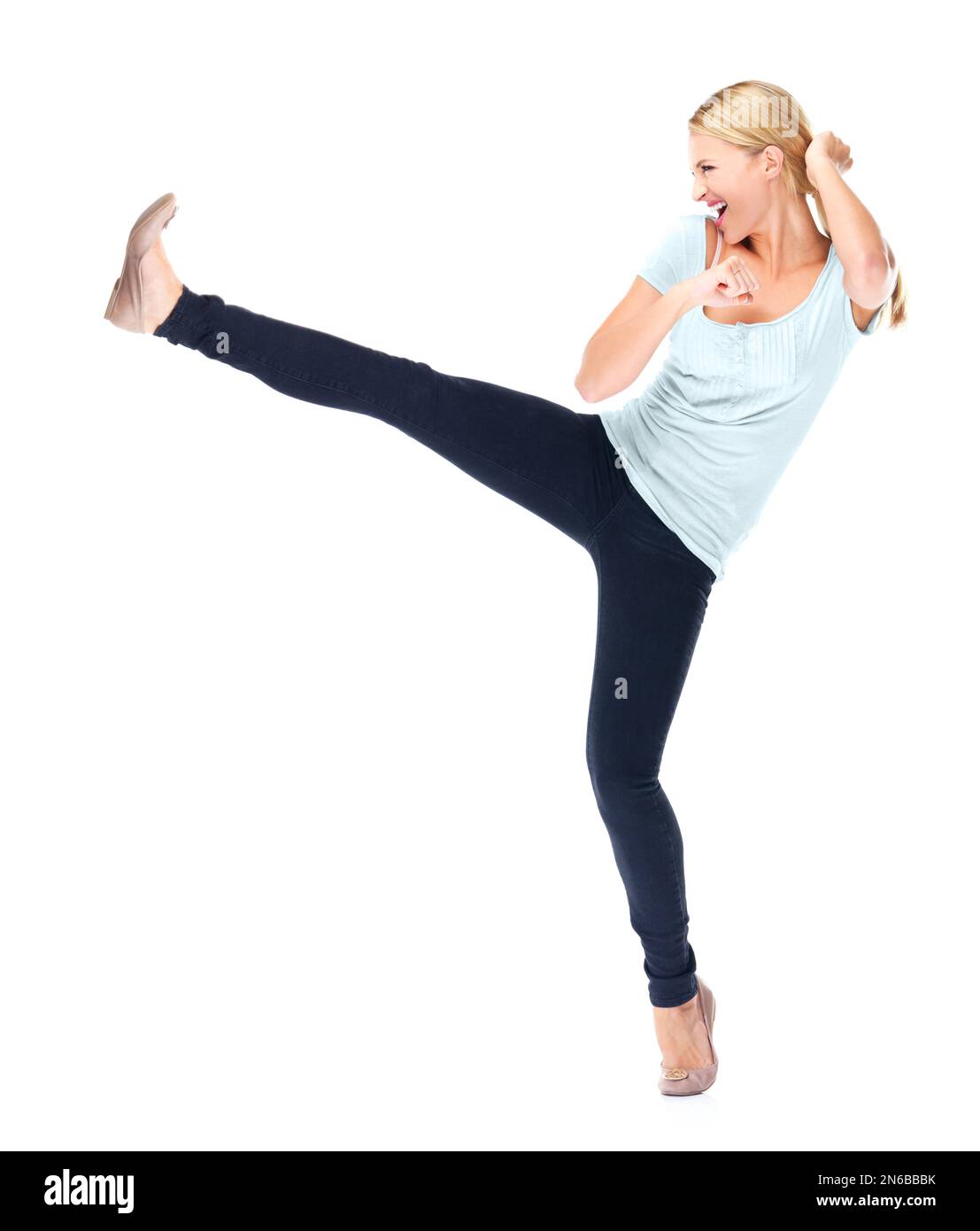 Kicking any blues away. Young woman giving a high kick while isolated ...