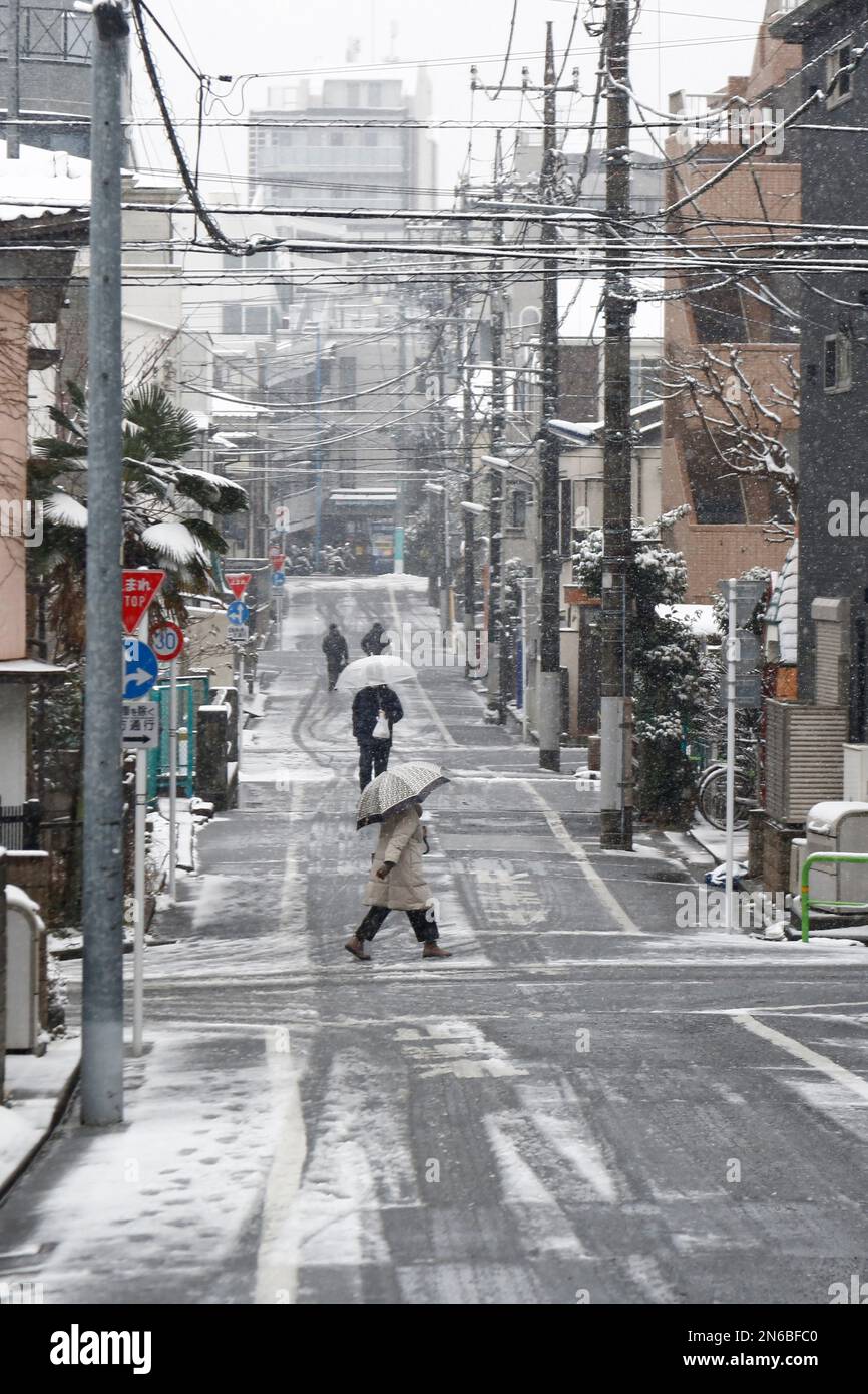 People holding umbrellas walk on a snow-covered sidewalk in Tokyo on ...