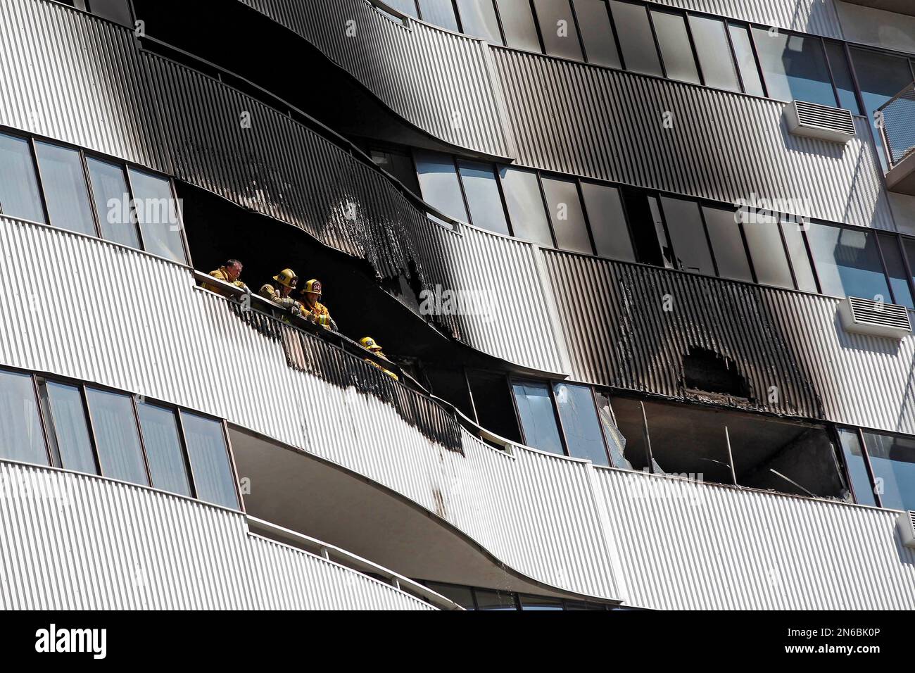 Los Angeles firefighters peer from a fire-damaged high rise apartment ...