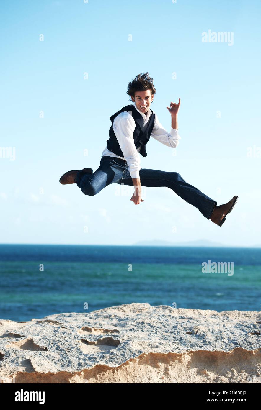 What a great feeling. Happy young man jumping in the air with the ocean ...