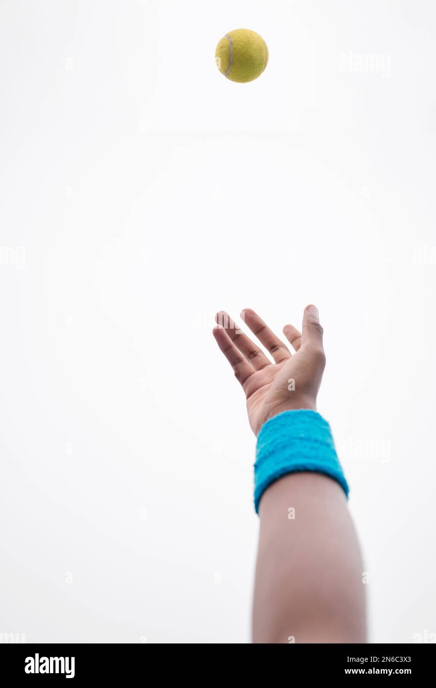 Hand of a tennis player throwing a ball into the air. African american ...