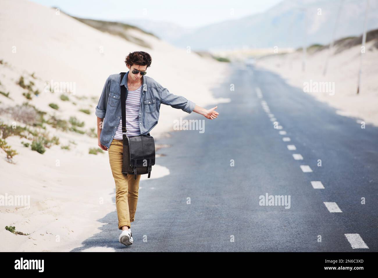 Not all those who wander are lost. Handsome young man hitchhiking while ...
