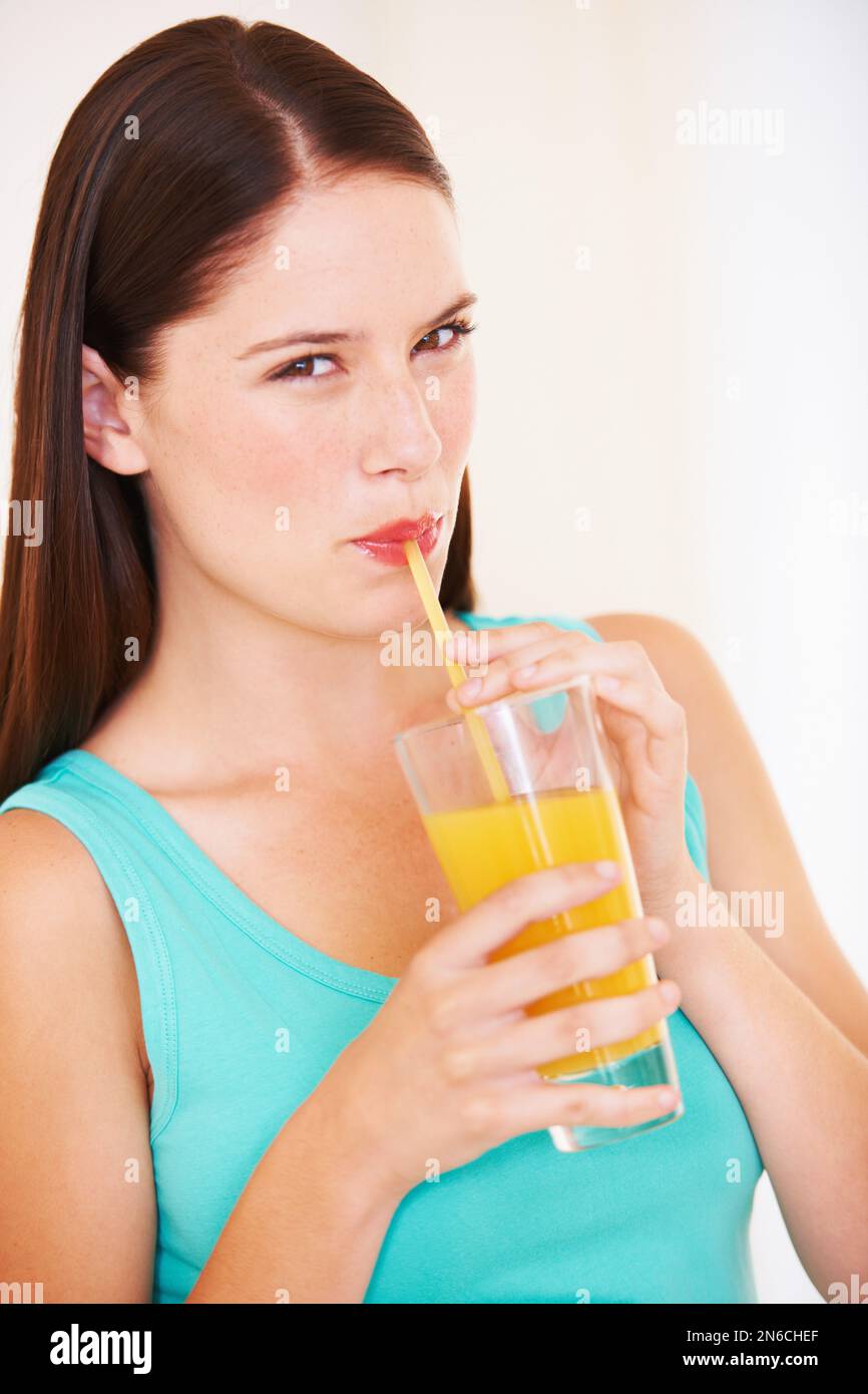 Enjoying a fresh glass of orange juice. Portrait of a beautiful young ...