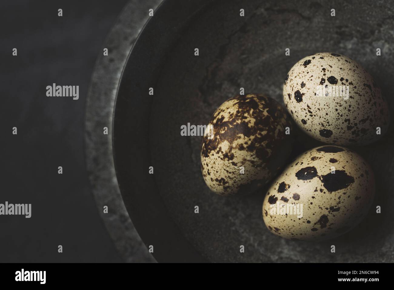 Fresh organic free range quail eggs in black stone bowl on black rustic ...