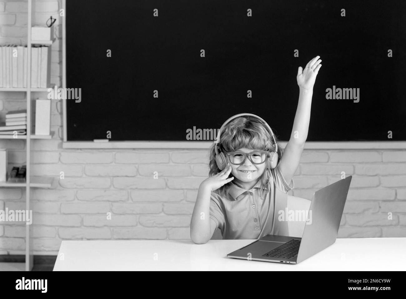 Cute little school kid boy with raised hand study in a classroom Stock ...