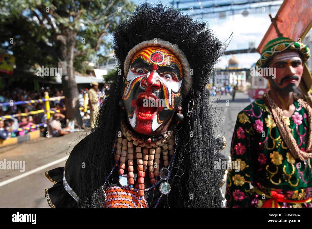 An Indian artist dressed as a devil gestures to the camera during a ...