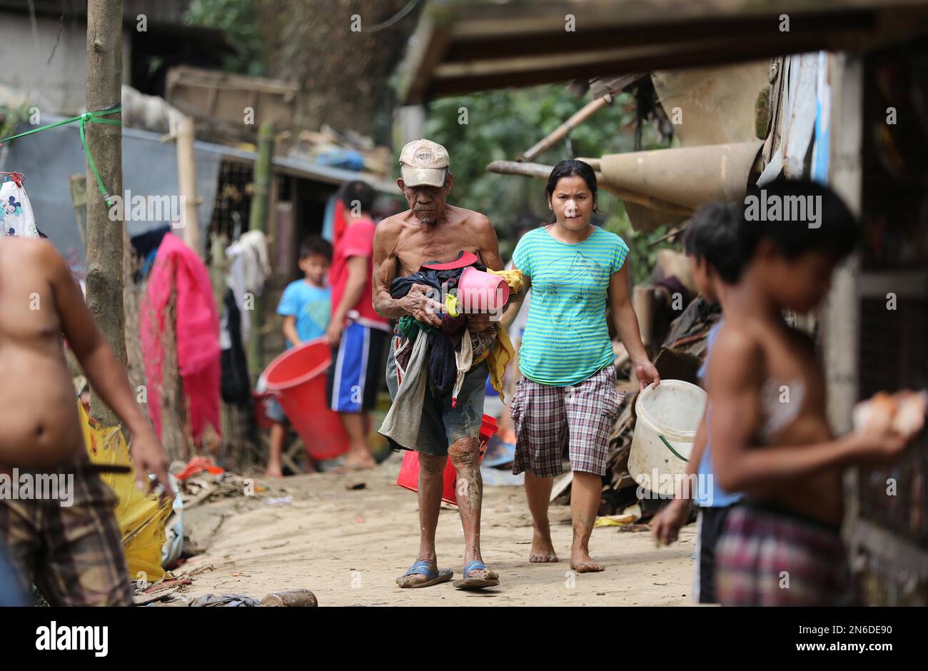 A Filipino resident carries muddied clothes which he salvaged from ...