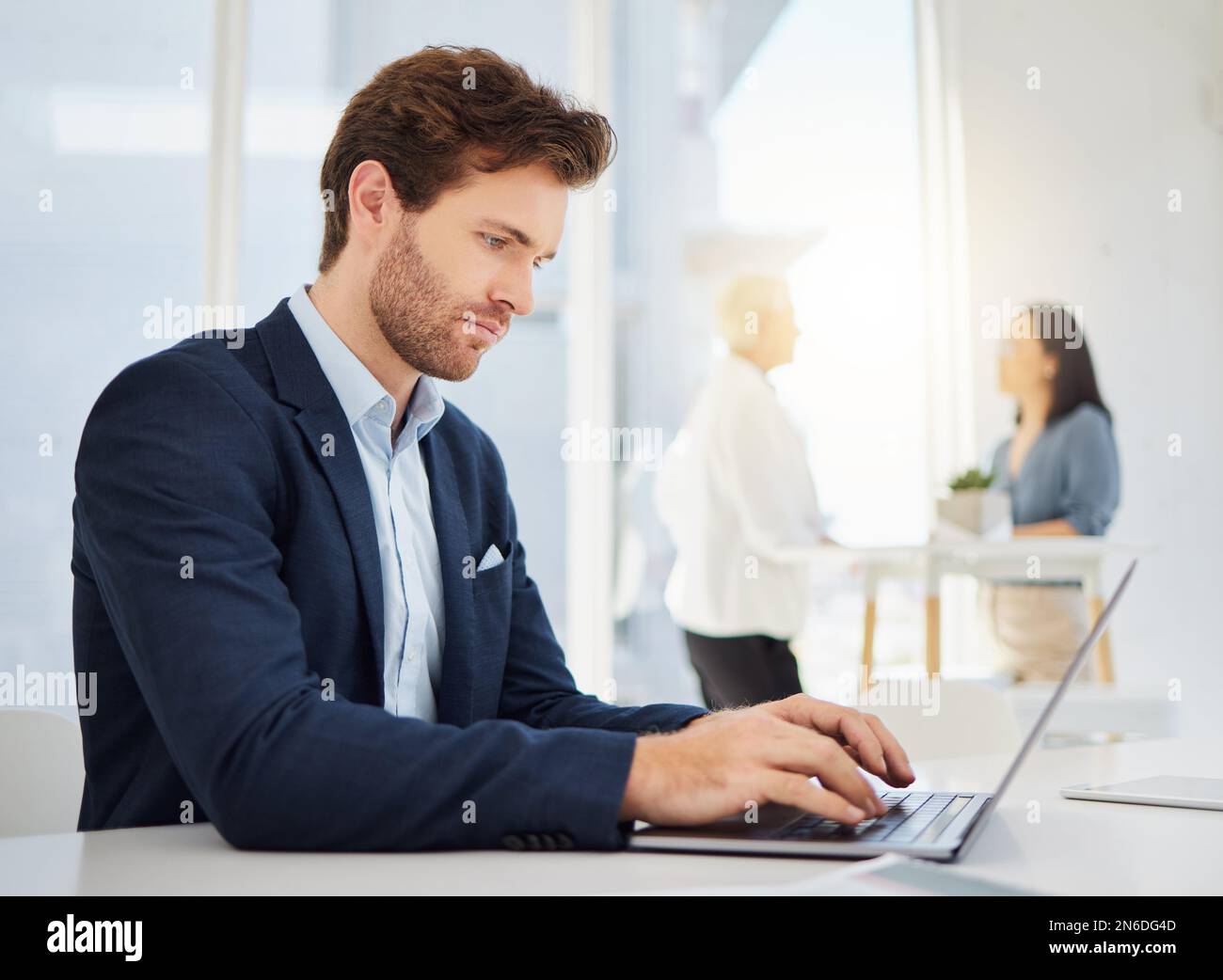 Focused young caucasian businessman typing on a laptop keyboard in an ...