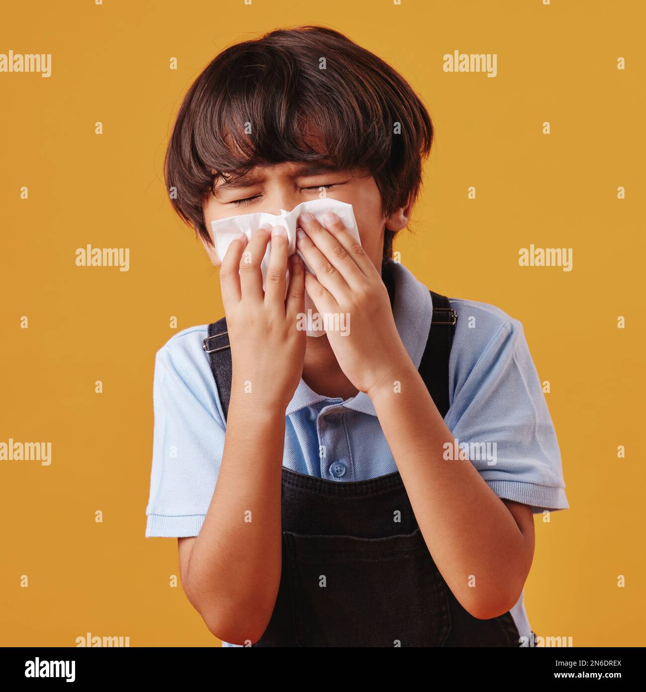 One mixed race Asian boy blowing his nose while looking sick and posing ...