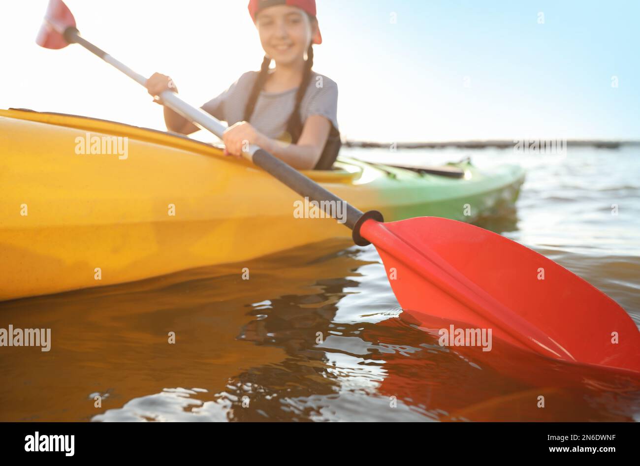 Little girl kayaking along river, focus on paddle. Summer camp activity ...