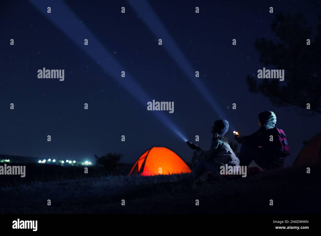 Couple with flashlights near camping tent outdoors at night Stock Photo ...