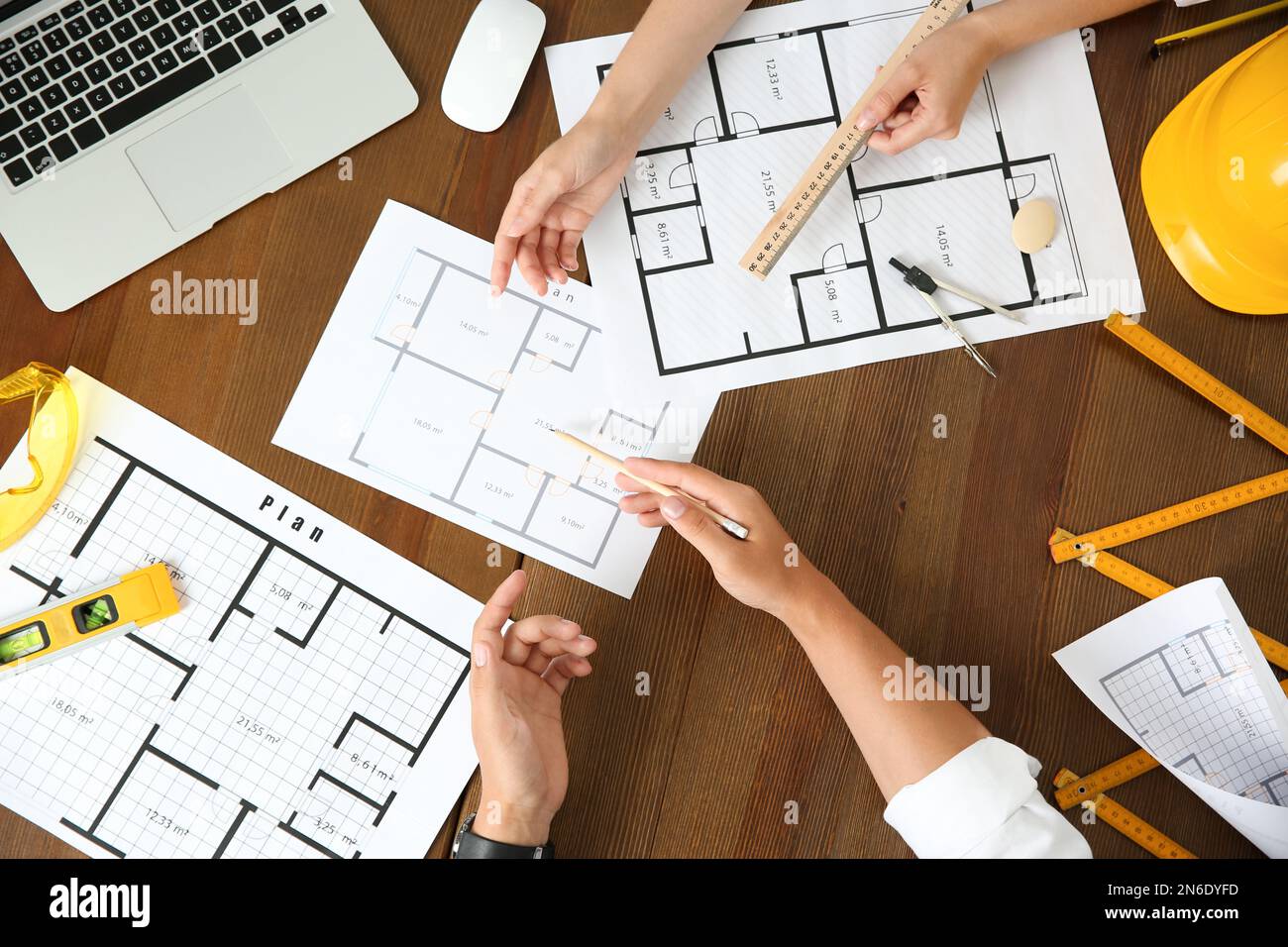 People working with construction drawings and tools at wooden table ...