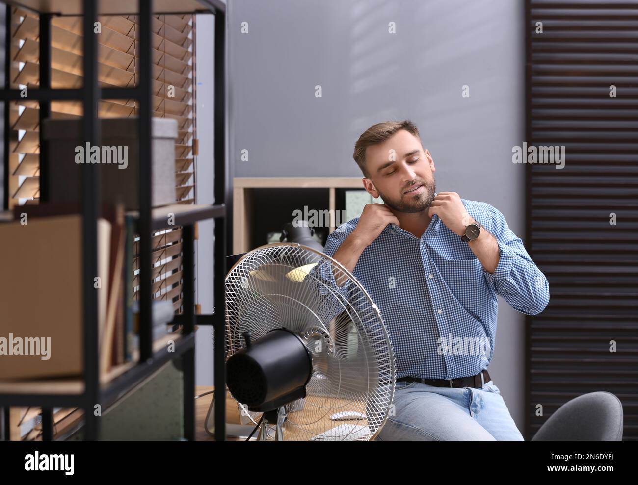 Man enjoying air flow from fan at workplace Stock Photo - Alamy