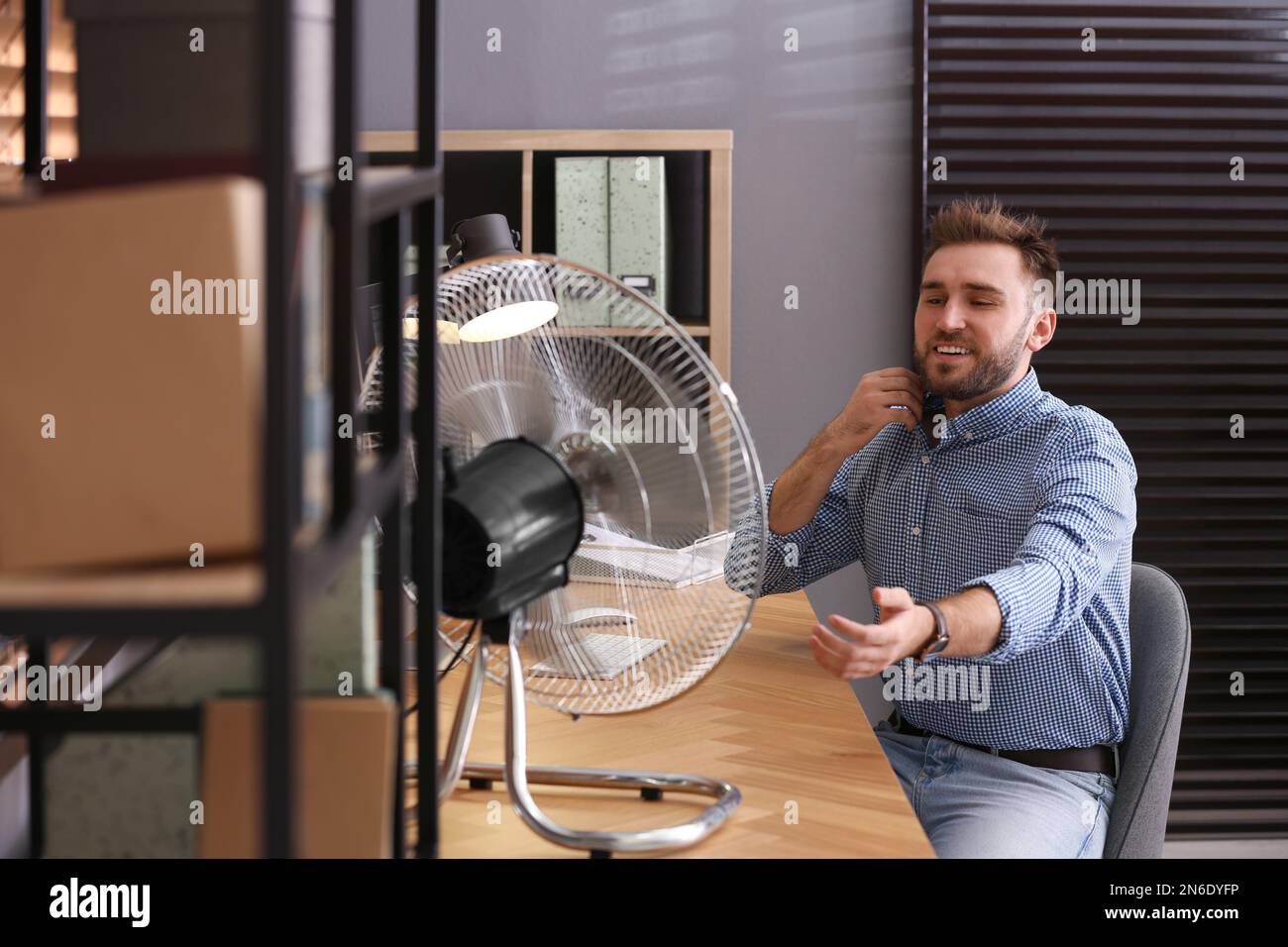 Man enjoying air flow from fan at workplace Stock Photo - Alamy