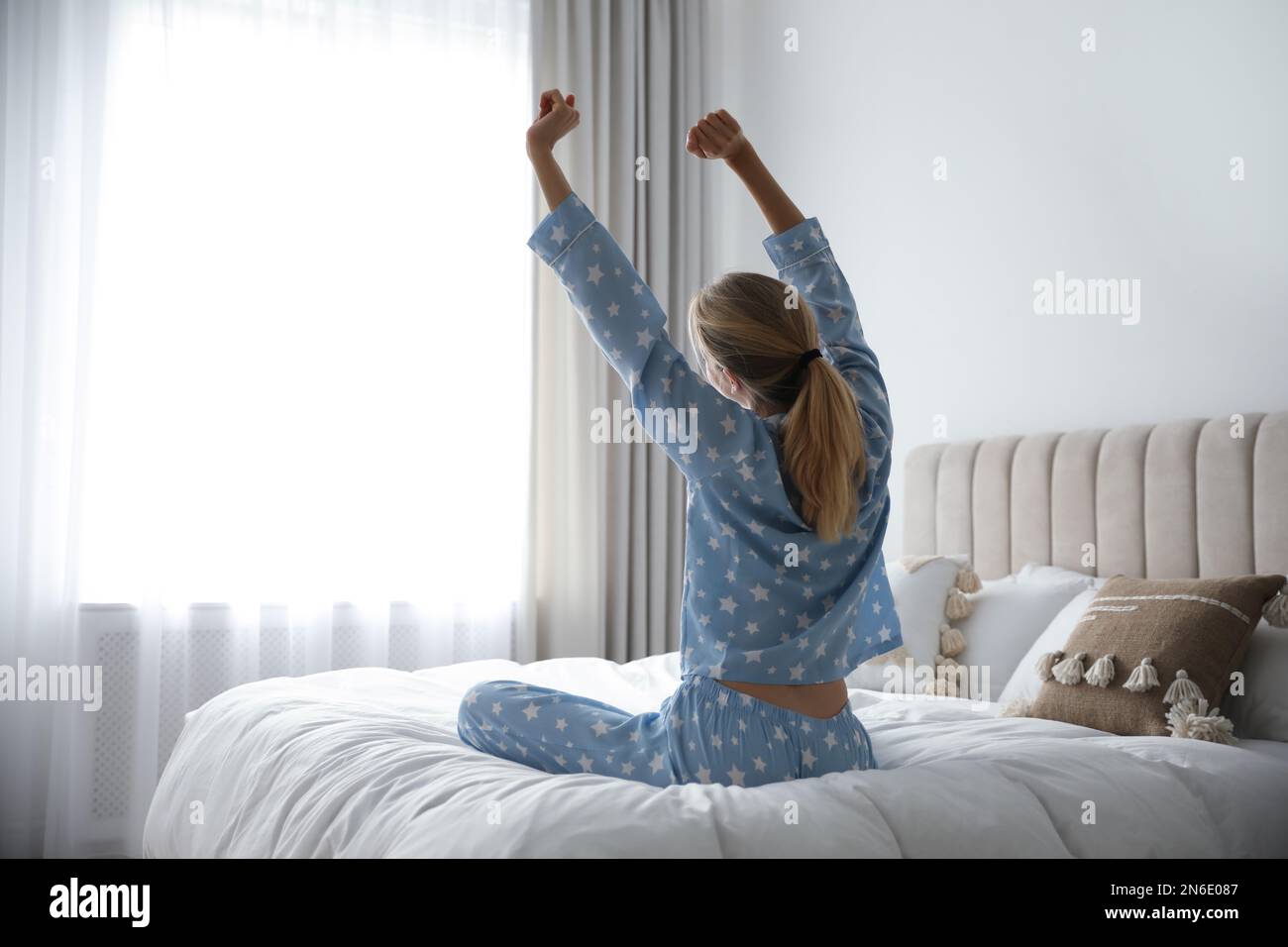 Young woman stretching on bed at home, back view. Morning fitness Stock ...