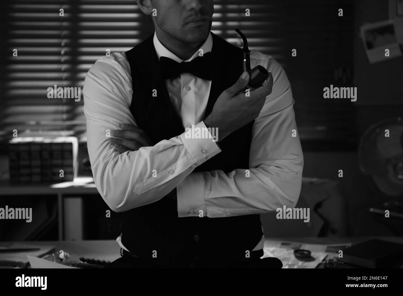 Old fashioned detective with smoking pipe in office, closeup. Black and ...