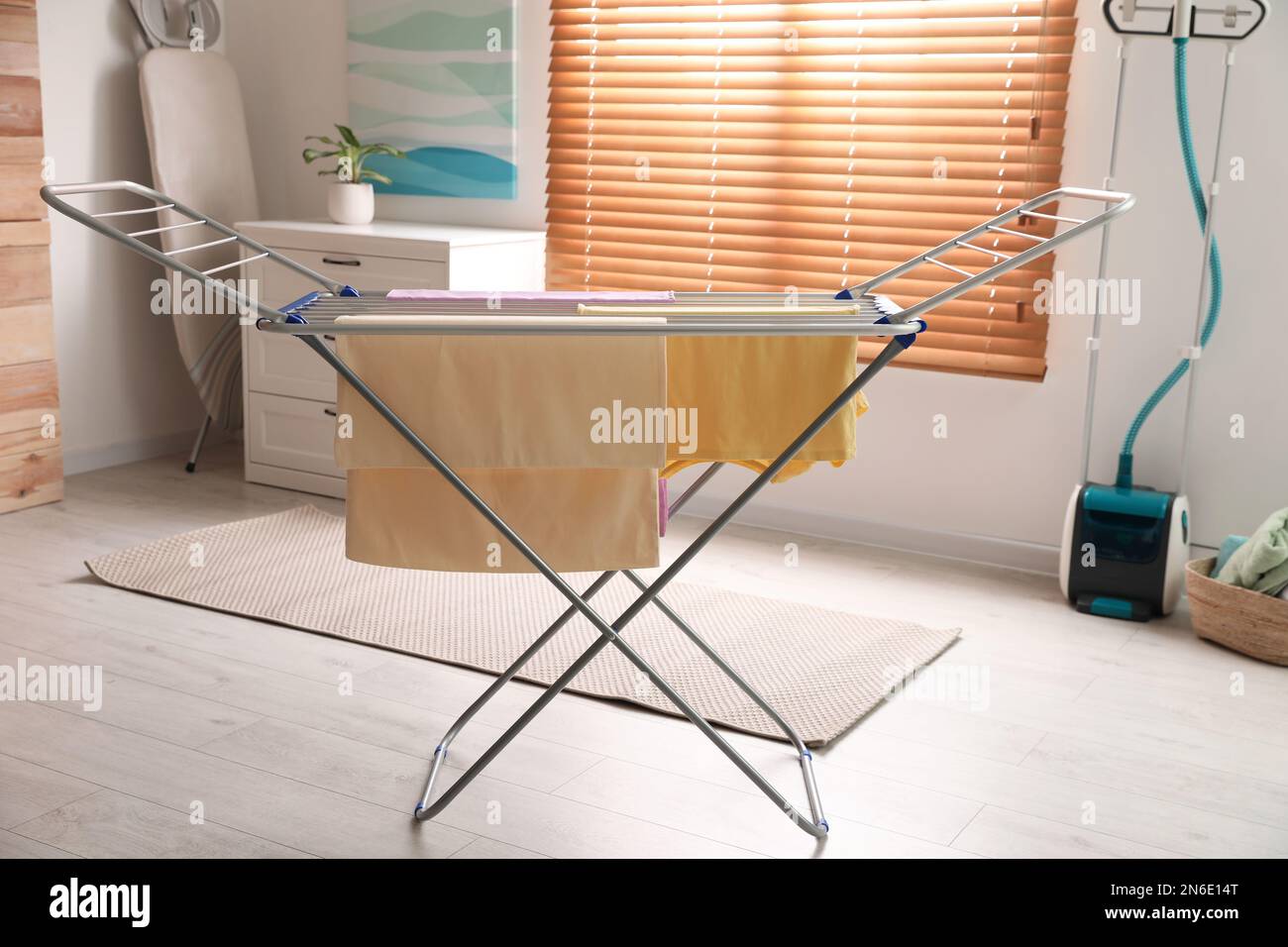 Clean laundry hanging on drying rack indoors Stock Photo - Alamy