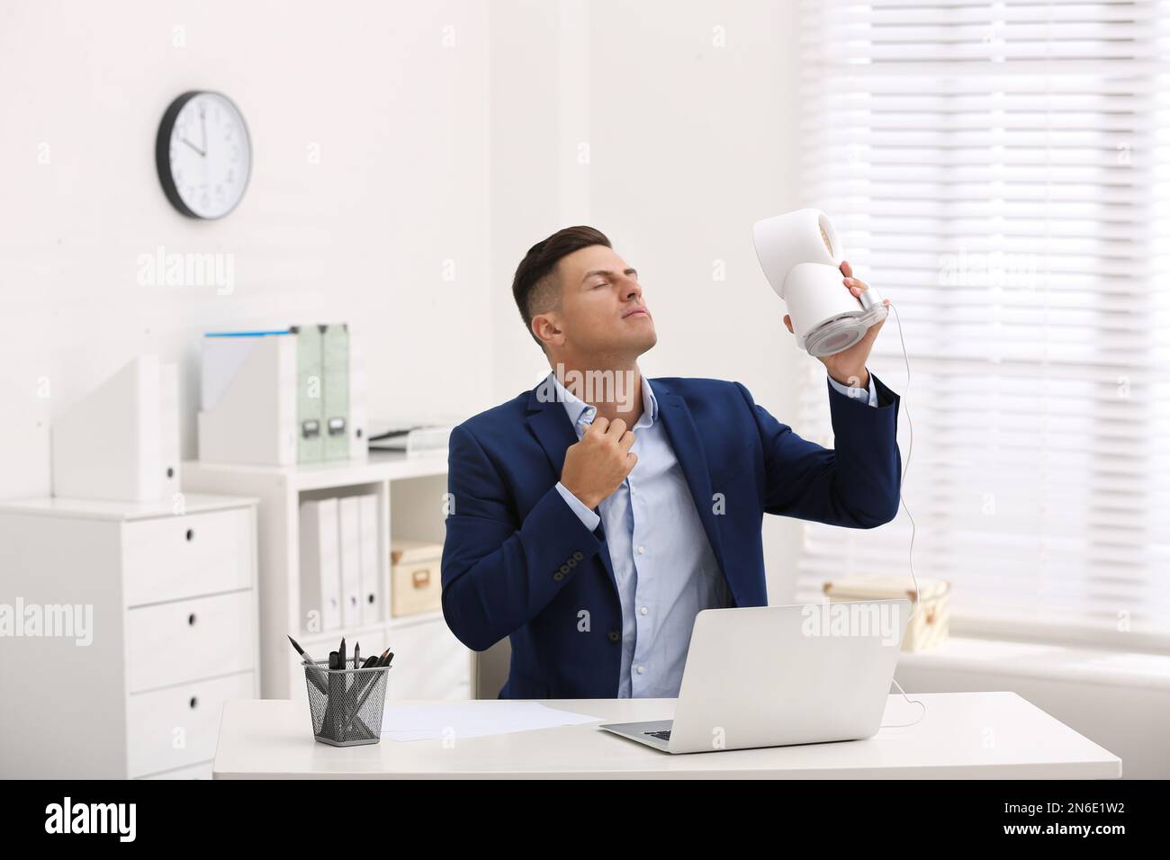 Man enjoying air flow from fan at workplace Stock Photo - Alamy