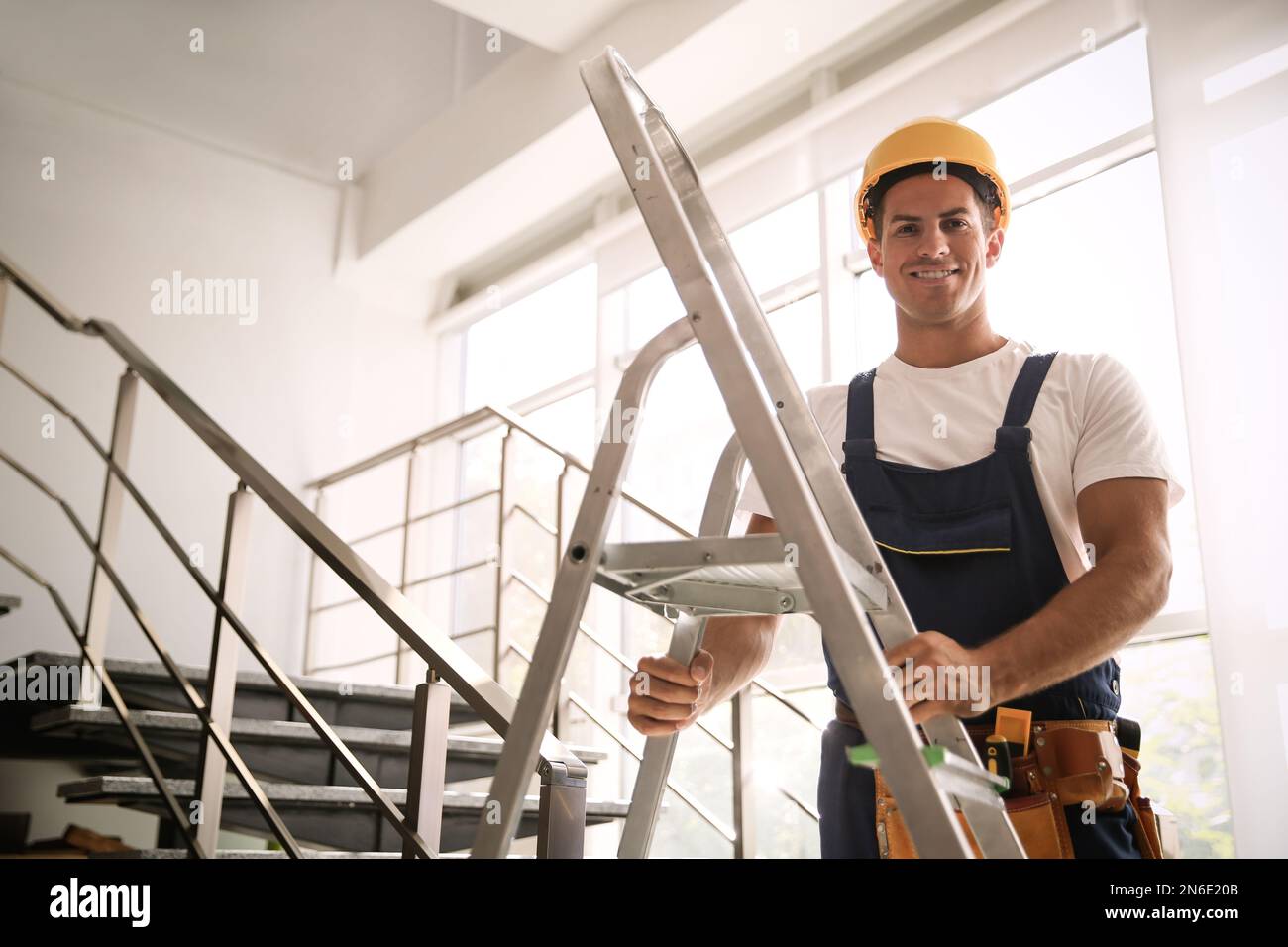 Professional builder with metal ladder on stairs Stock Photo - Alamy