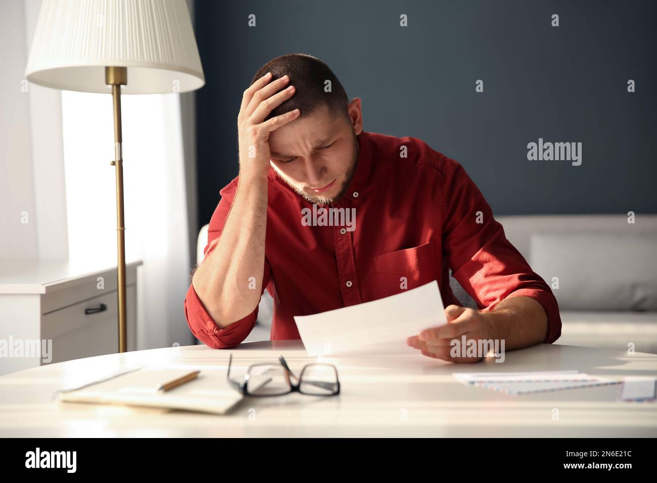 Man reading paper letter at white table in room Stock Photo - Alamy