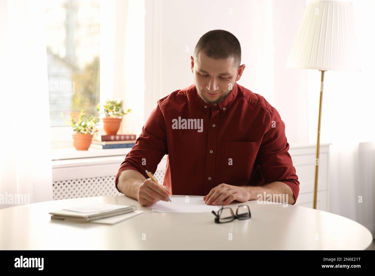 Man writing letter at white table in room Stock Photo - Alamy