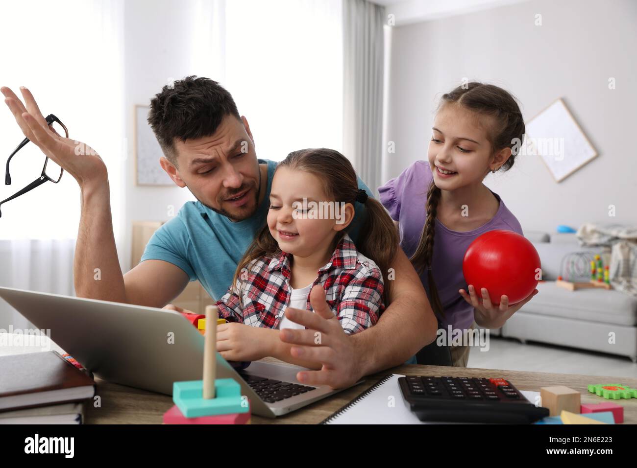 Children disturbing stressed man in living room. Working from home ...