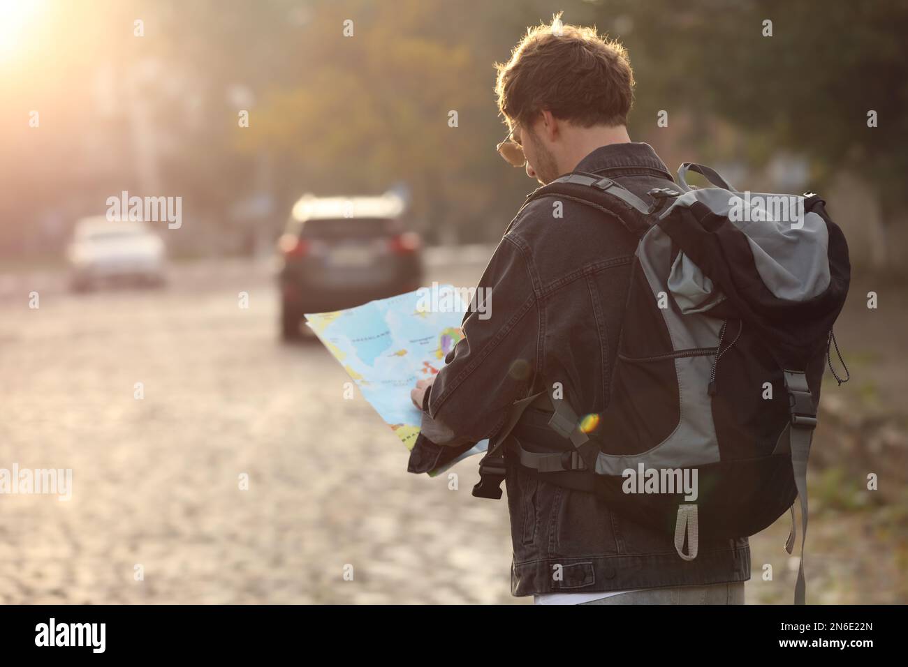 Traveler with world map on city street, back view Stock Photo - Alamy