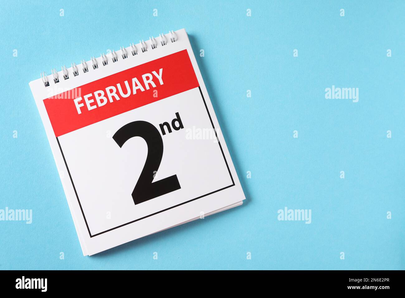 Top view of calendar with date February 2nd on light blue background ...