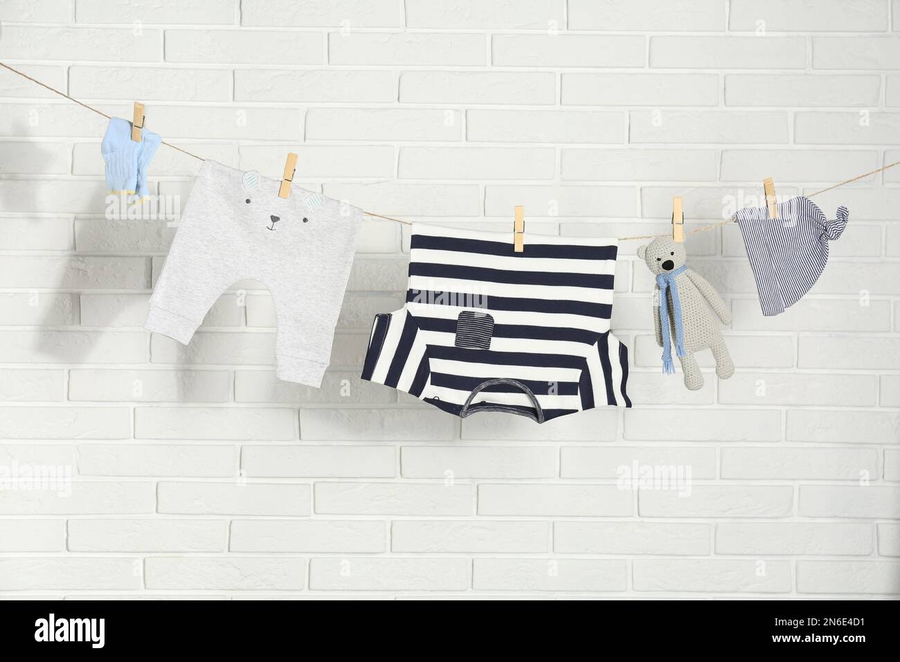 Baby clothes hanging on washing line near white brick wall Stock Photo ...