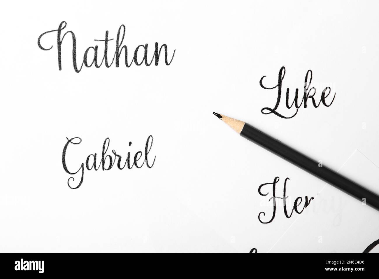 Ordinary pencil and different baby names written on paper, top view ...