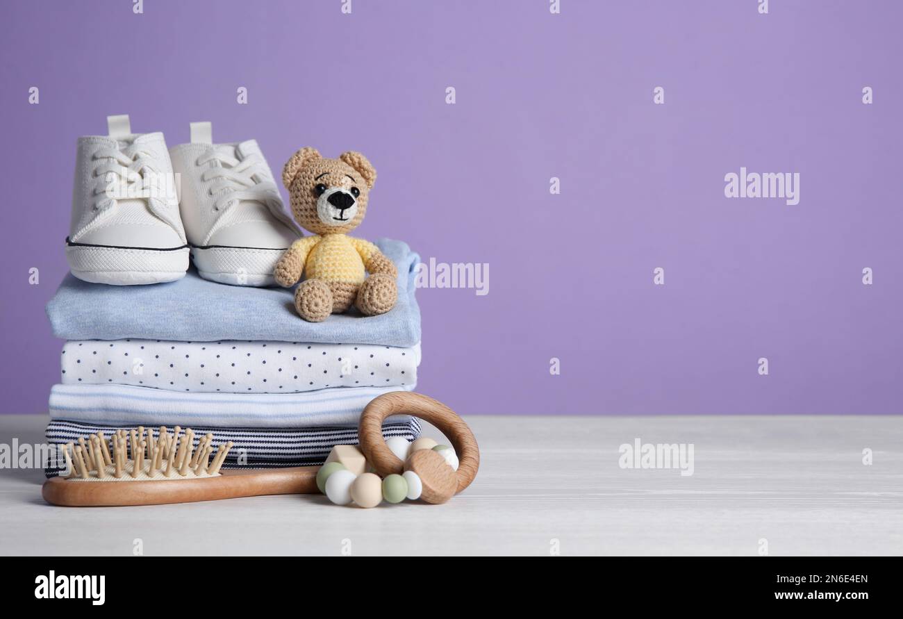 Children's shoes, stack of clothes and toys on white wooden table ...