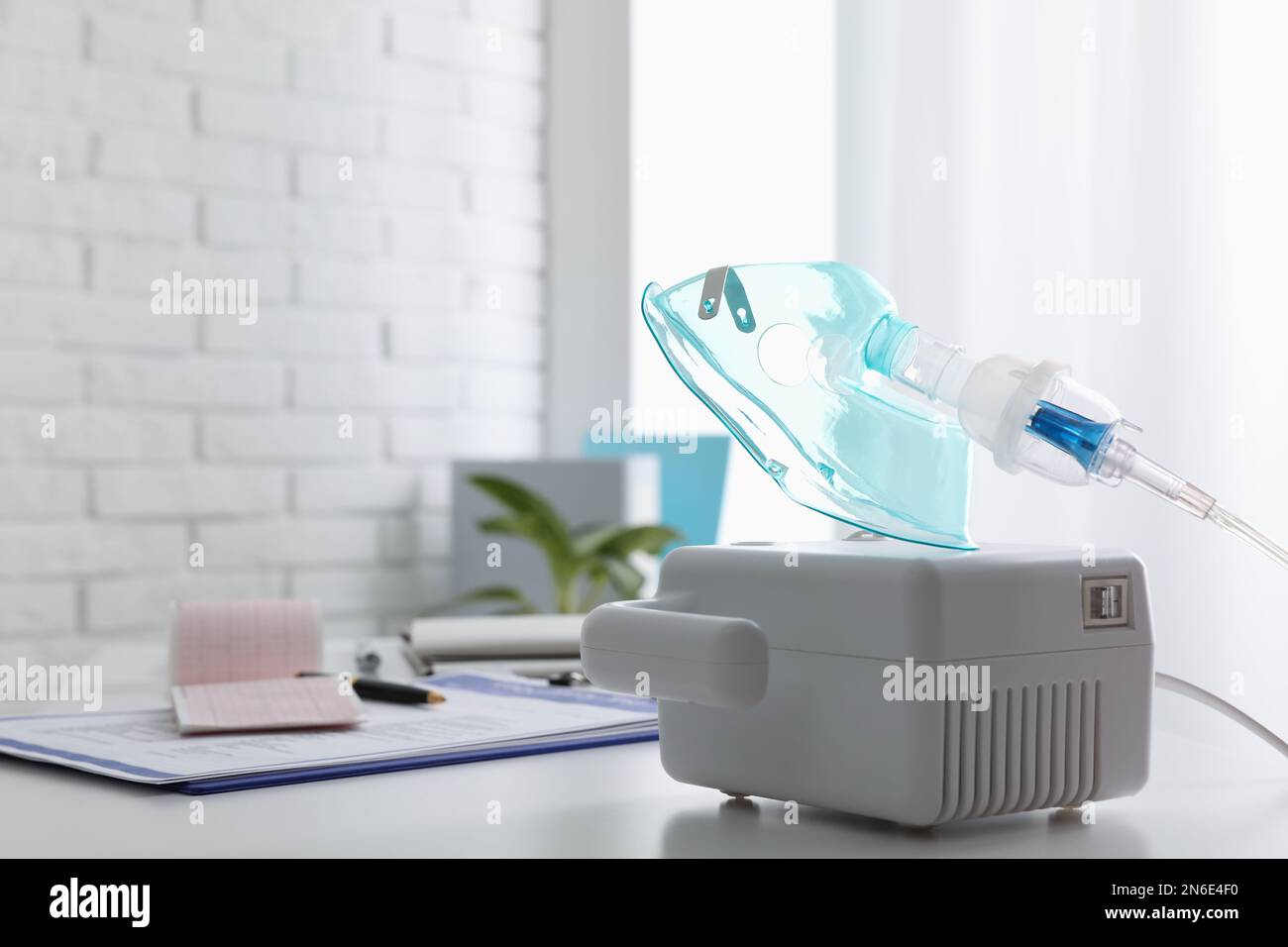 Modern nebulizer with face mask on white table indoors, space for text ...