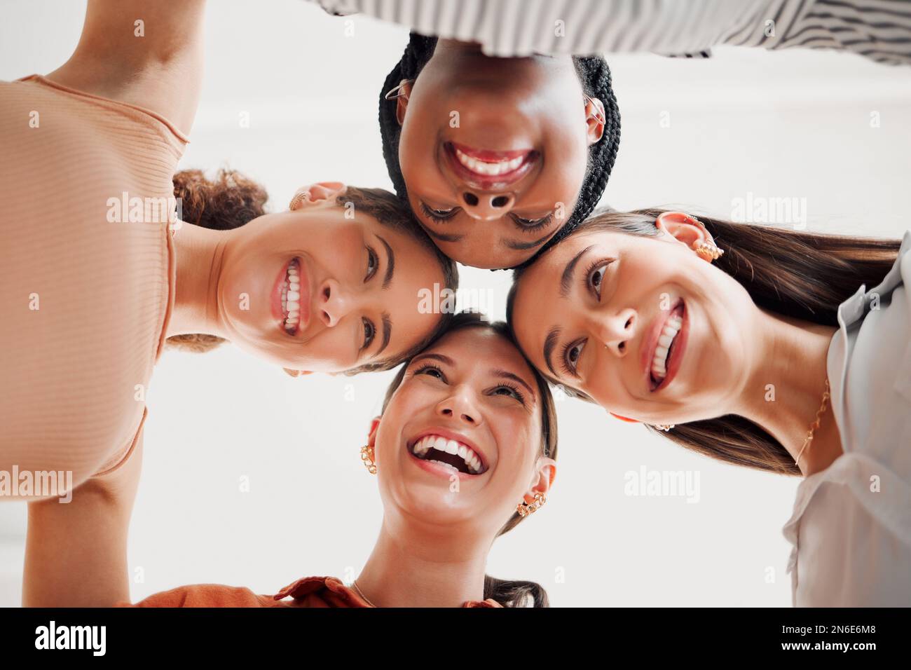 Group of happy businesswomen joining their heads together in a circle ...