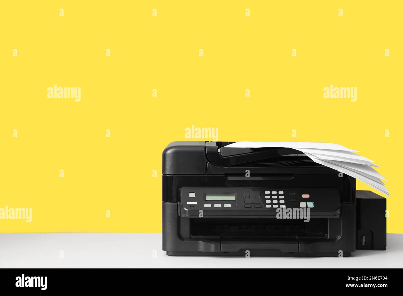 New modern printer with paper on yellow background. Space for text ...