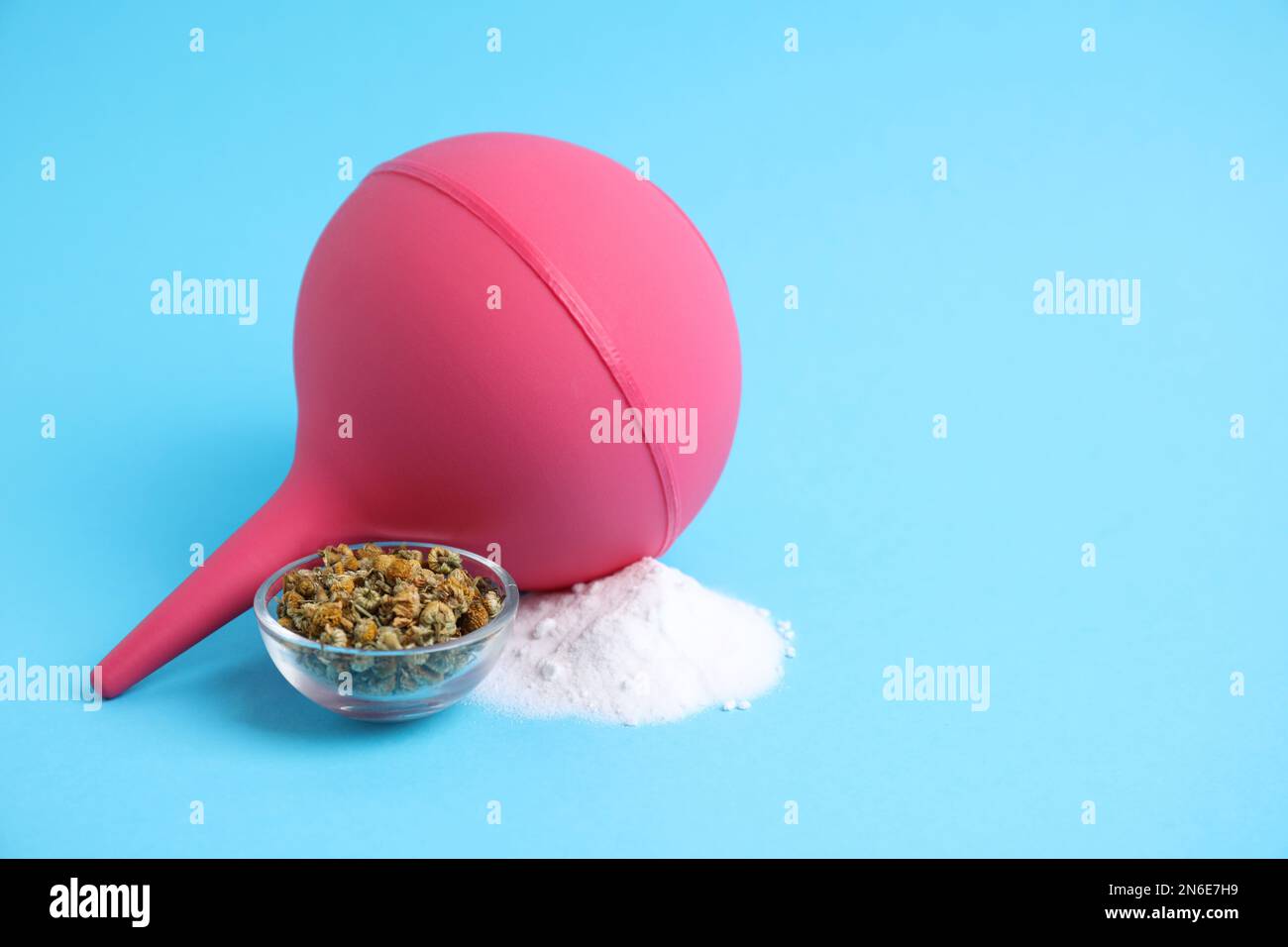 Pink enema, soda powder and dry chamomile flowers on light blue ...