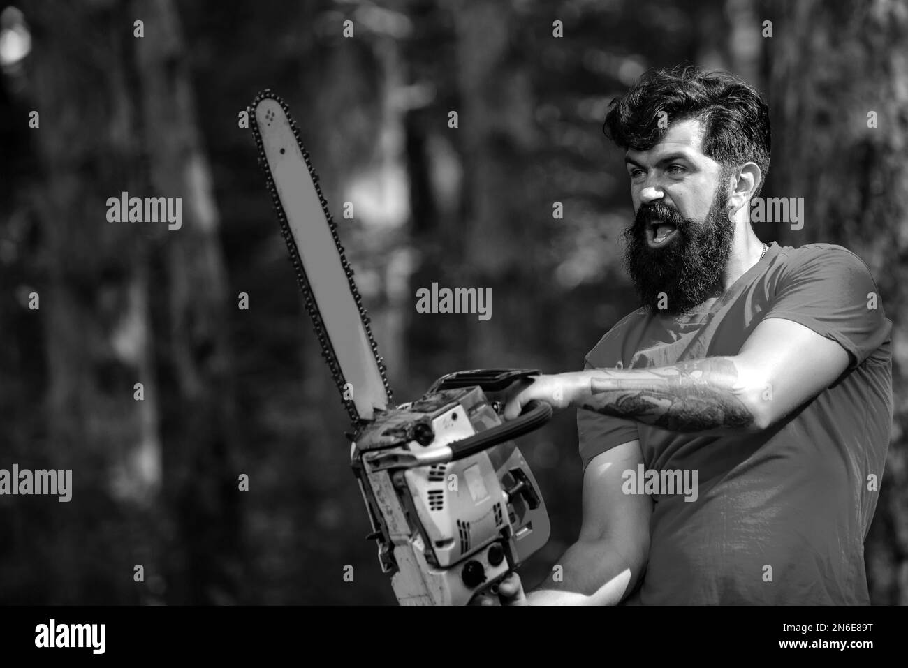 Lumberjack on serious face carries chainsaw. Woodcutter with chainsaw ...