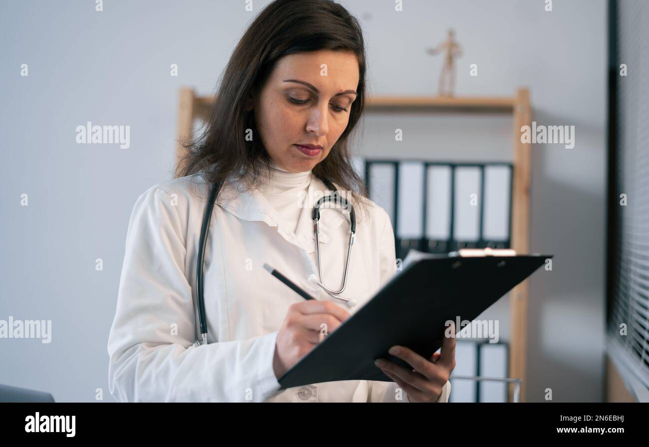 Indian doctor in white coat holding clipboard and writing diagnosis ... Indian doctor in white coat holding clipboard and writing diagnosis ...