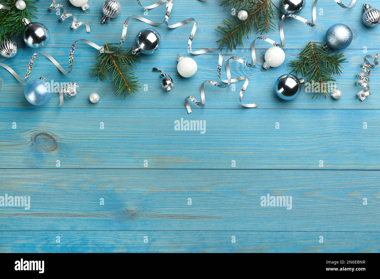 Shiny serpentine streamers, Christmas balls and fir branches on blue ...