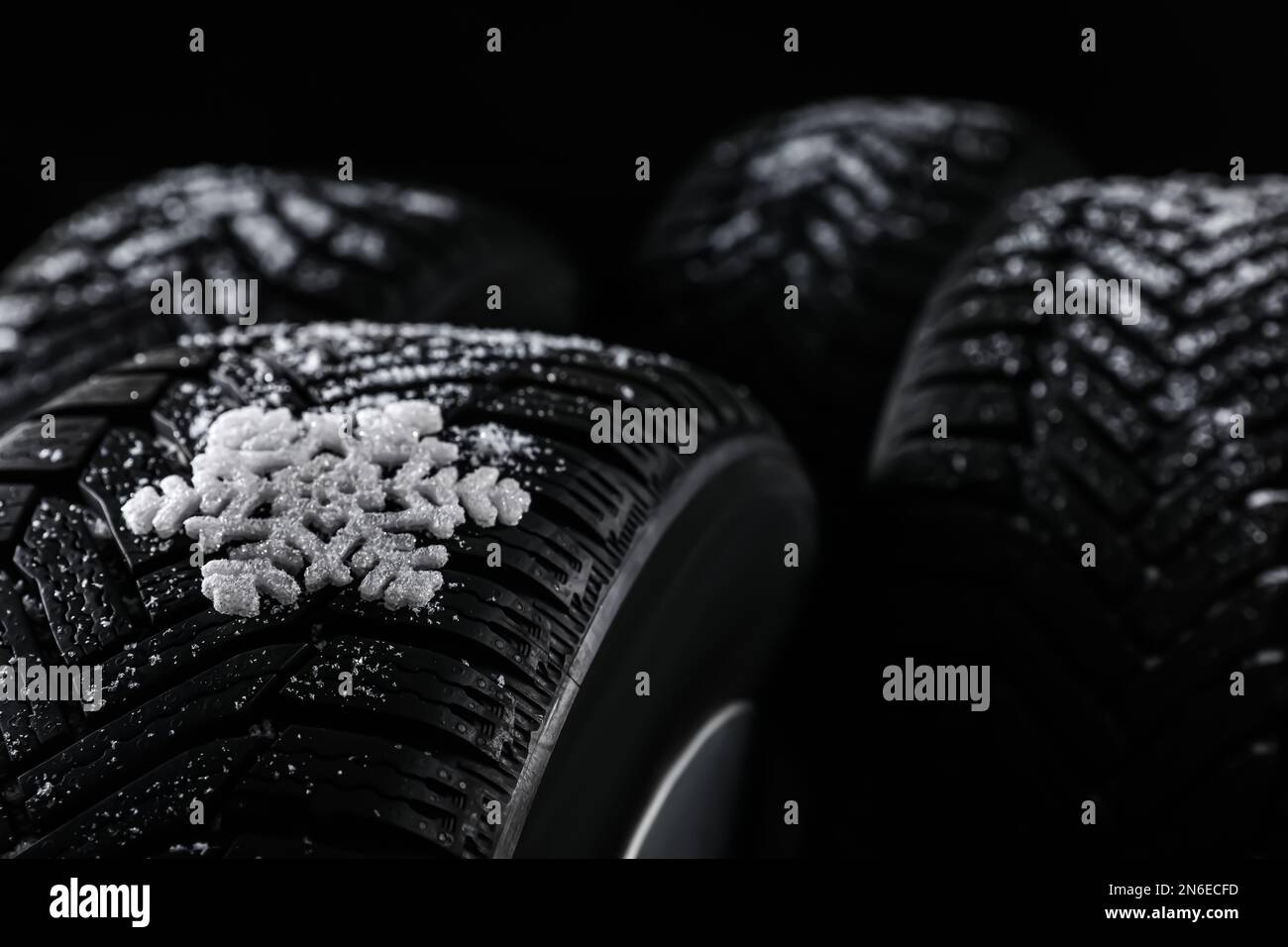 Snowy set of wheels with winter tires on black background, closeup ...