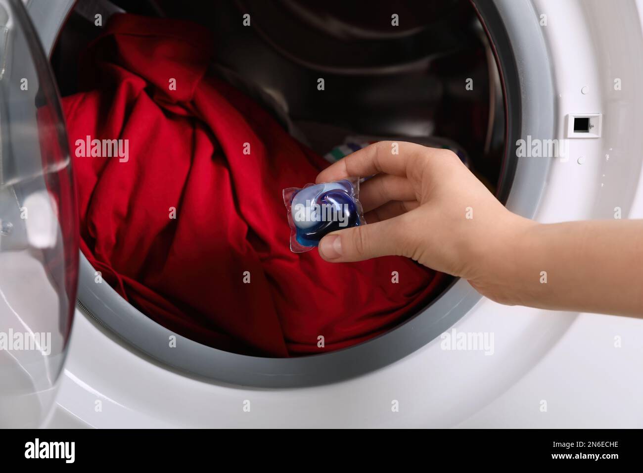 Woman putting laundry detergent capsule into washing machine, closeup ...