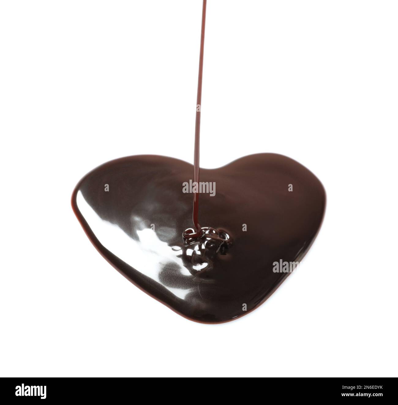 Pouring chocolate syrup into heart shaped puddle on white background ...