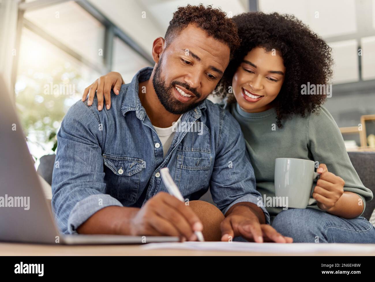 Young Happy Mixed Race Couple Going Through Documents And Using A