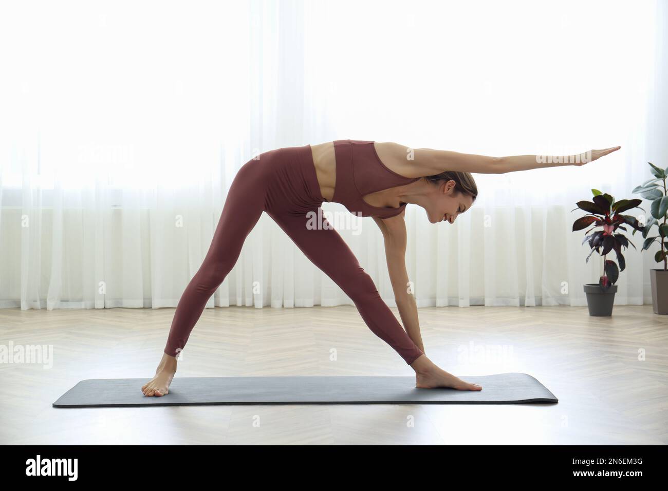 Young woman practicing triangle asana in yoga studio. Trikonasana pose ...