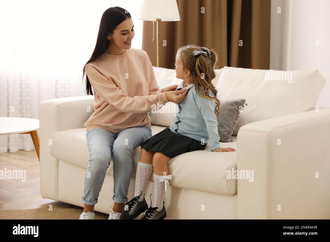 Young mother helping her little child get ready for school at home ...