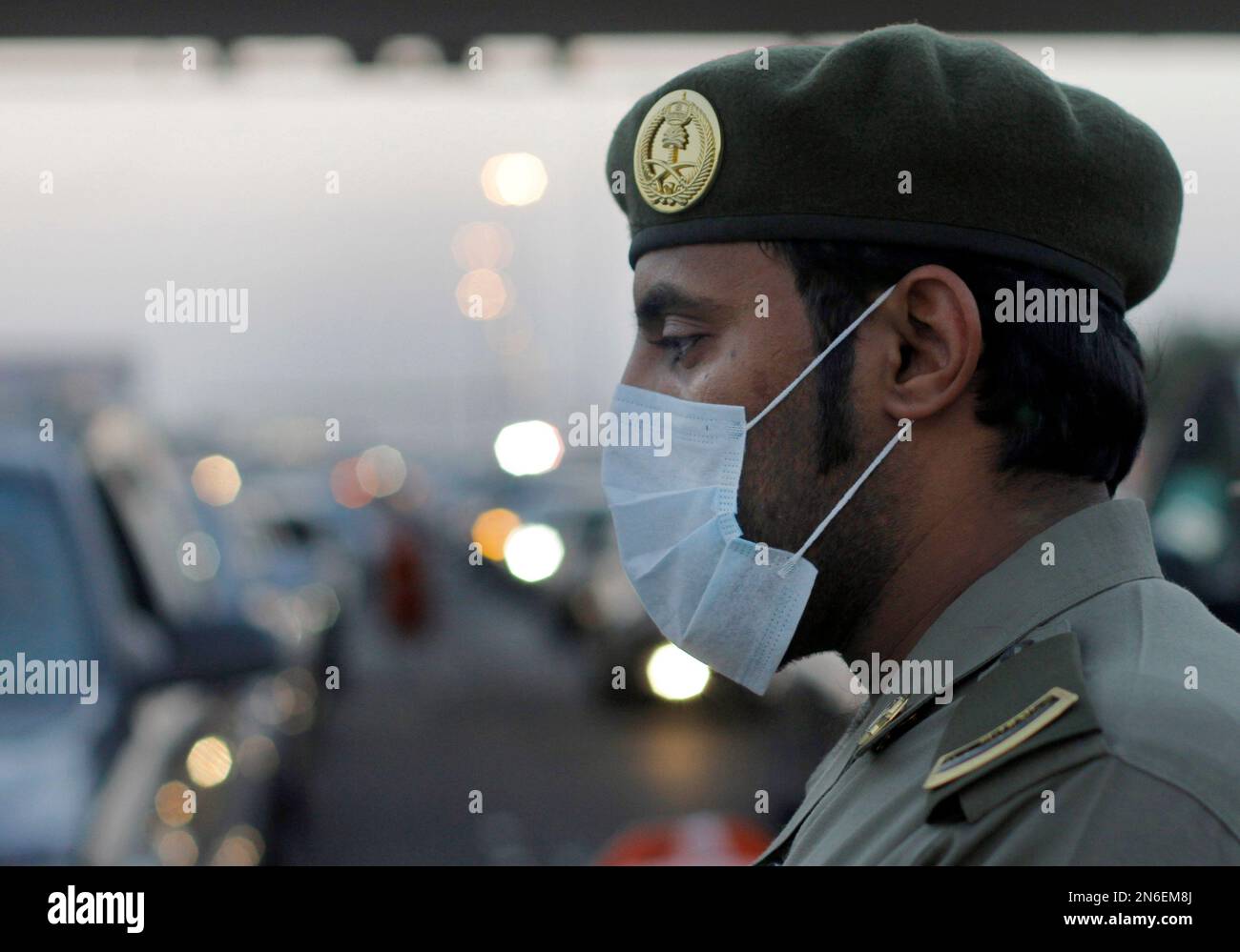 A Saudi police officer wears a surgical mask as he checks passengers ...