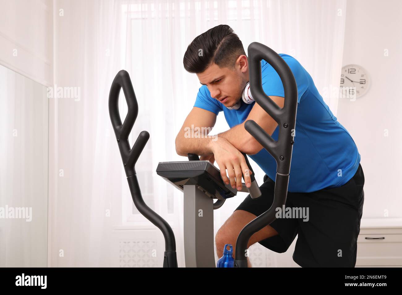 Tired man after training on modern elliptical machine at home Stock ...