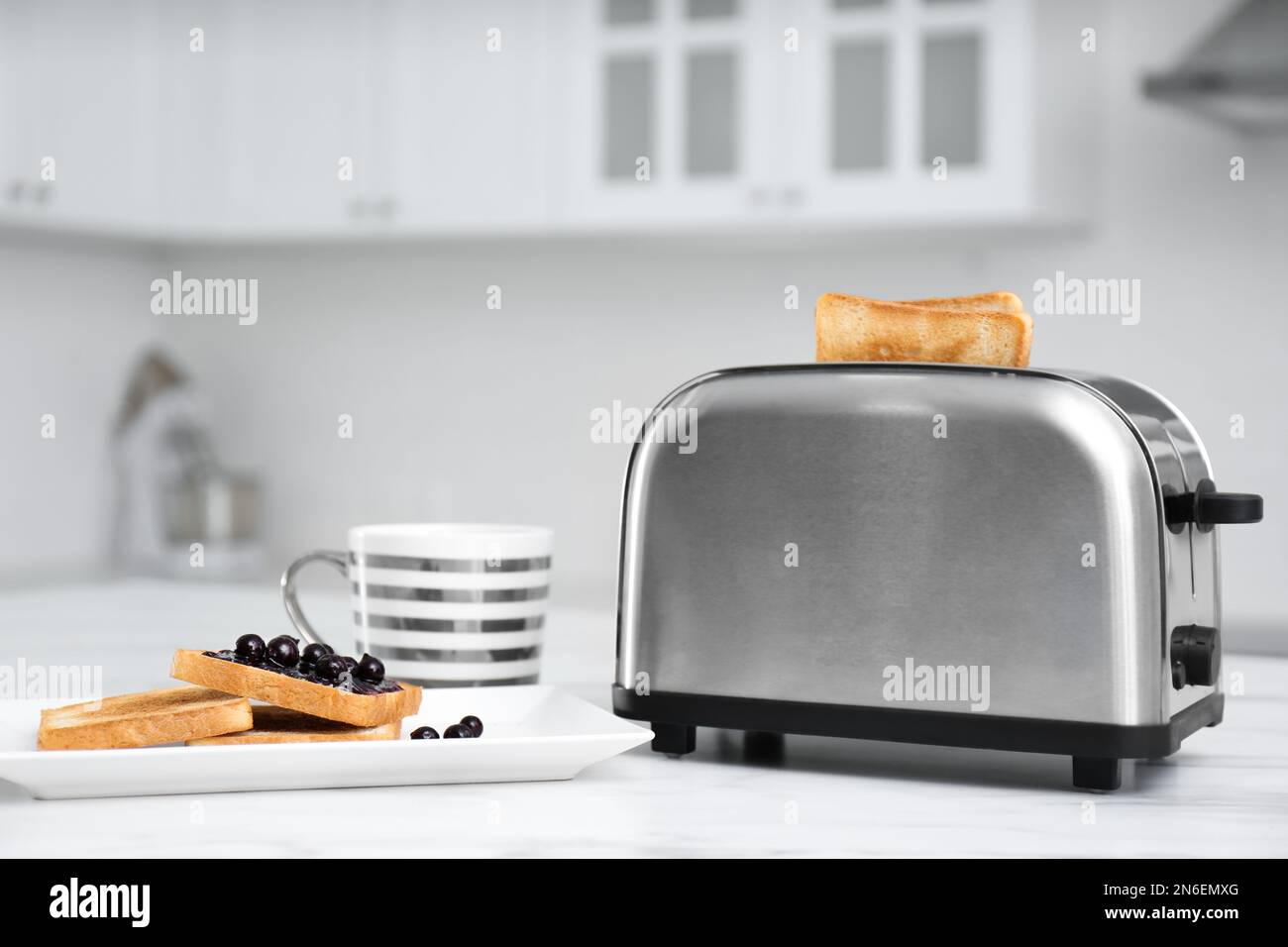 Modern toaster and tasty breakfast on white table in kitchen Stock ...