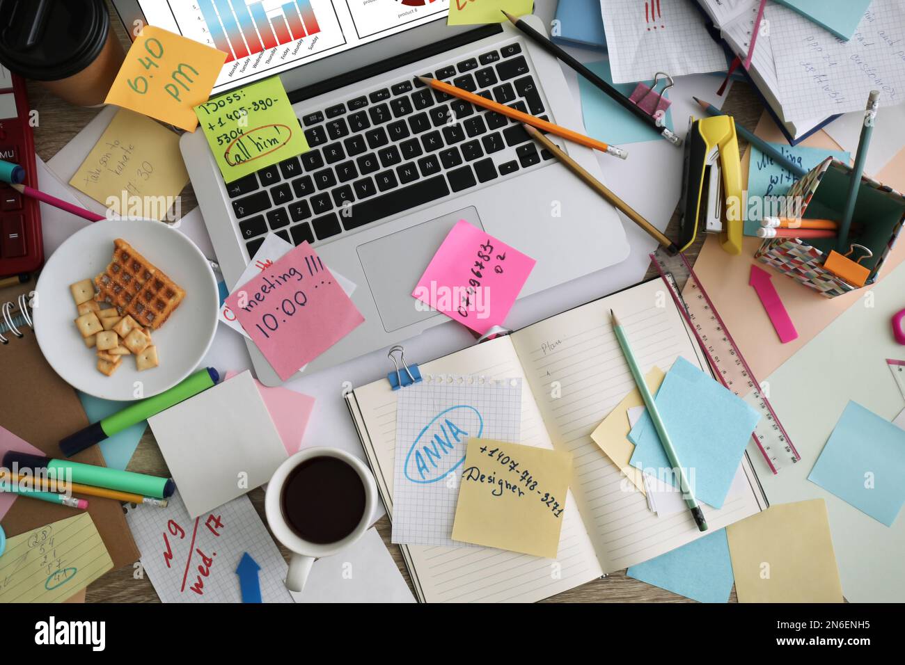 Laptop, notes and office stationery in mess on desk, top view ...