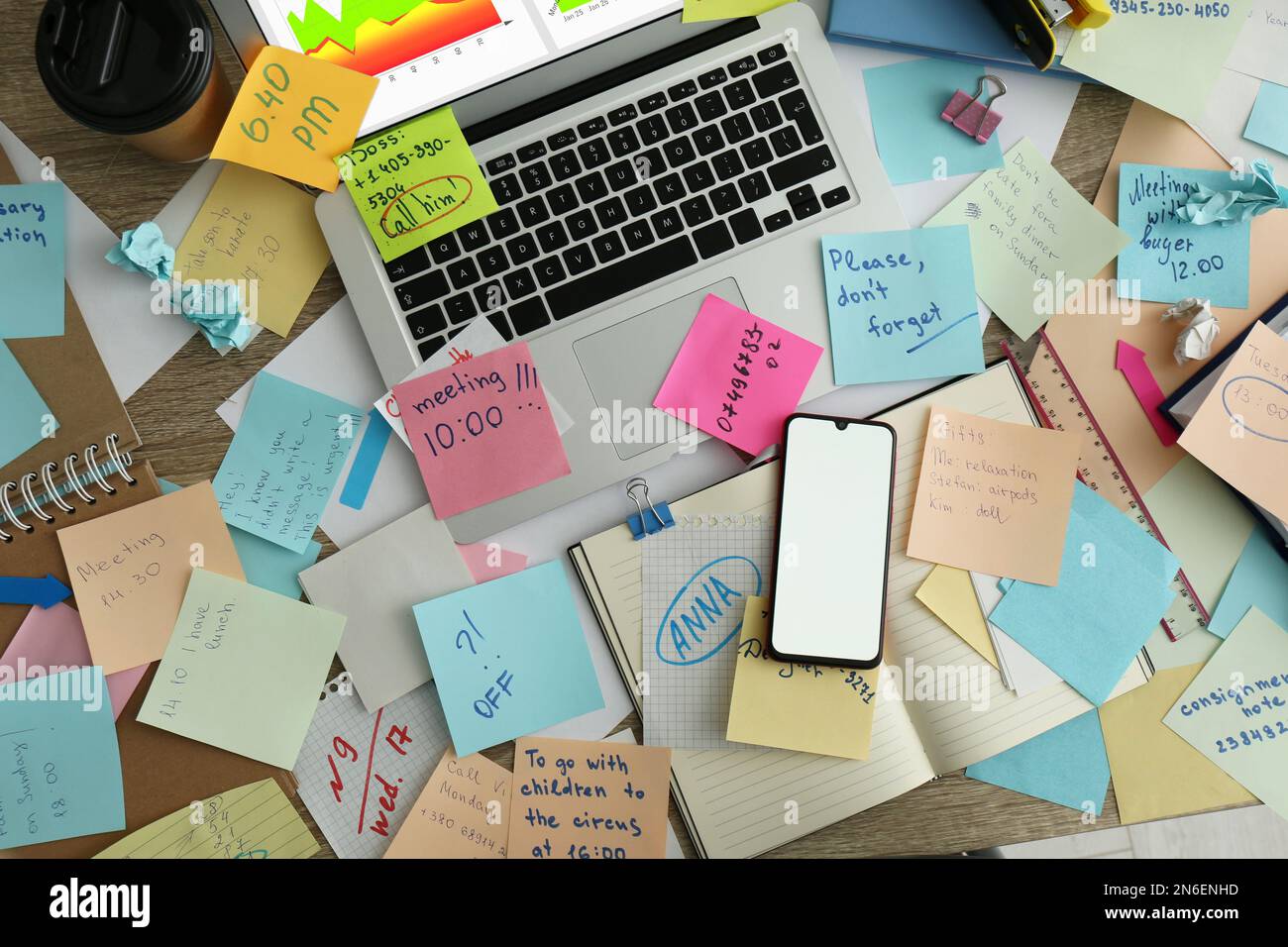 Laptop, smartphone, notes and office stationery in mess on desk, top ...