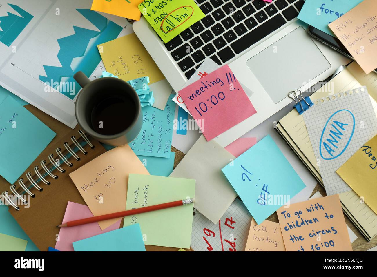Laptop, notes and office stationery in mess on desk, top view ...